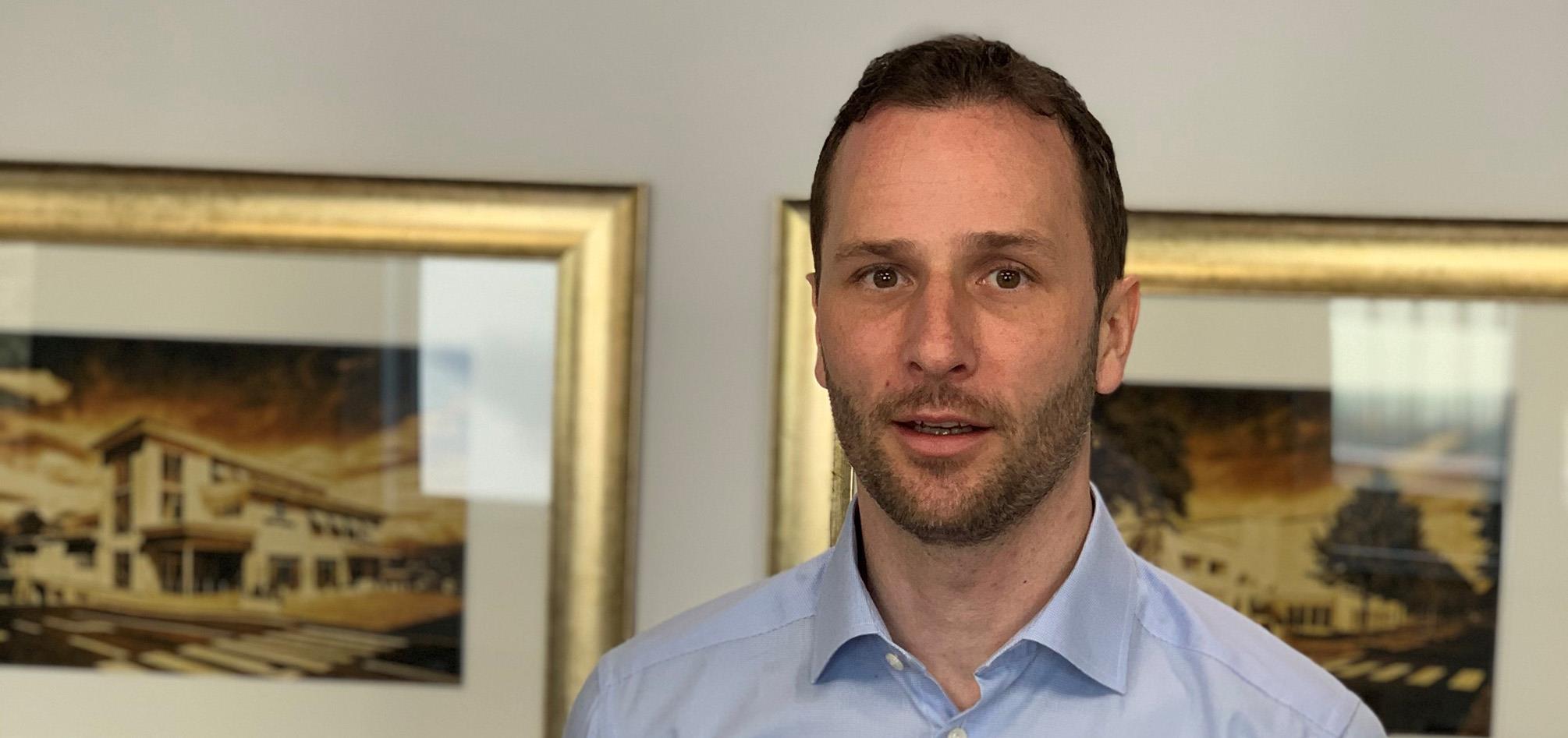 Marcus i blå skjorta framför två tavlor i guldram